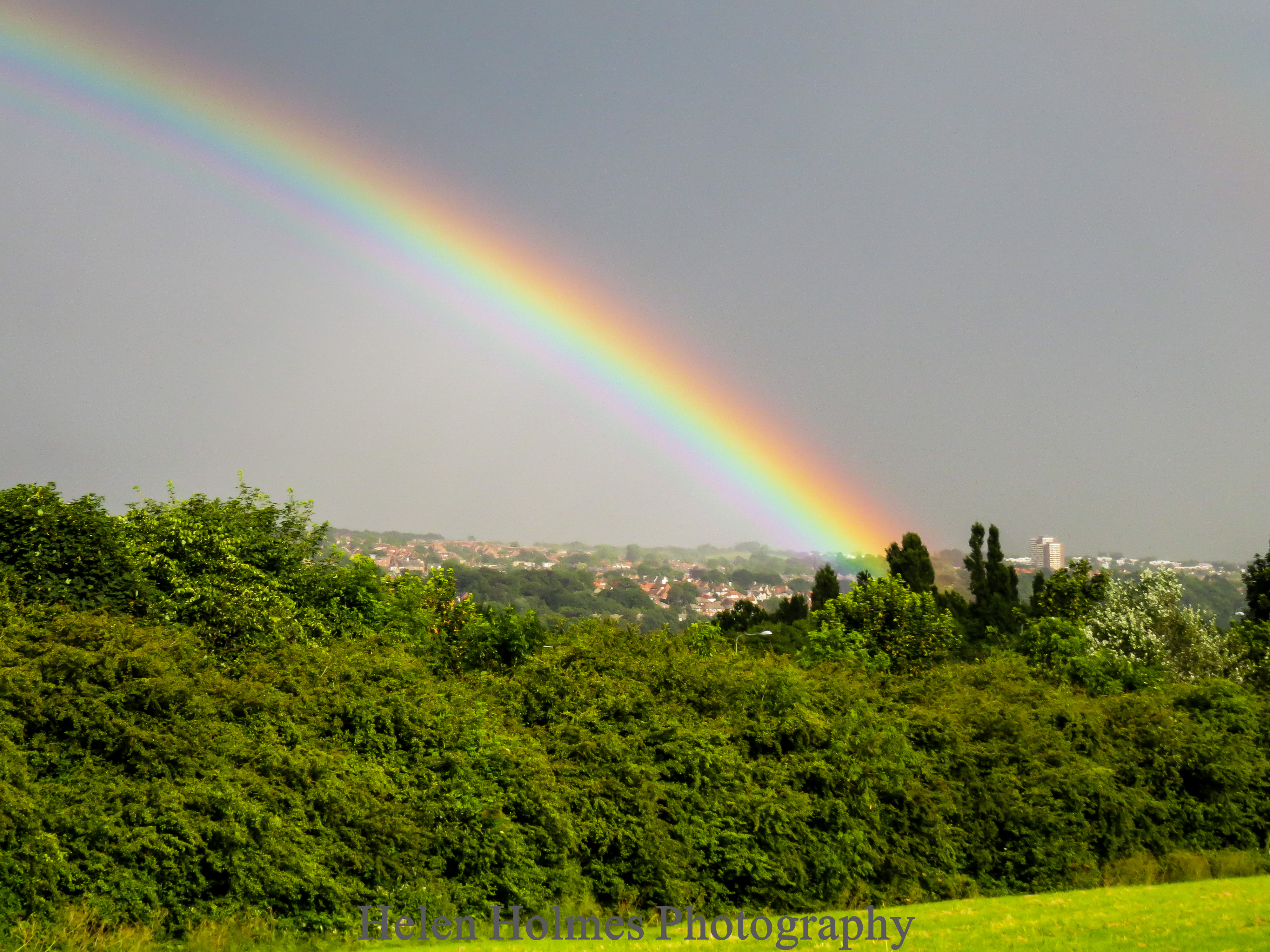 Storm clouds on one side and clear blue sky on the other. Rainbows are ...